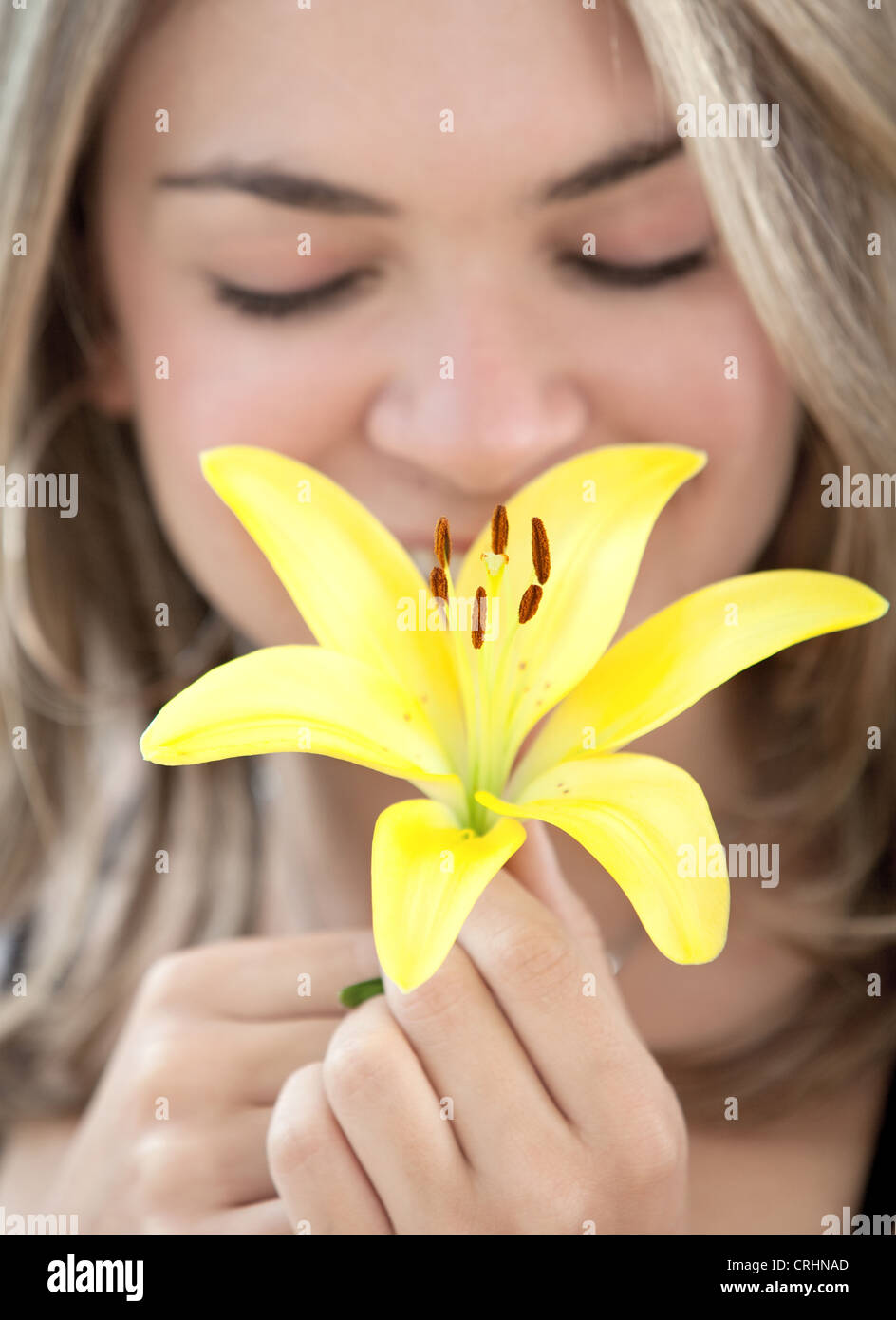 young woman smelling at yellow lily Stock Photo - Alamy