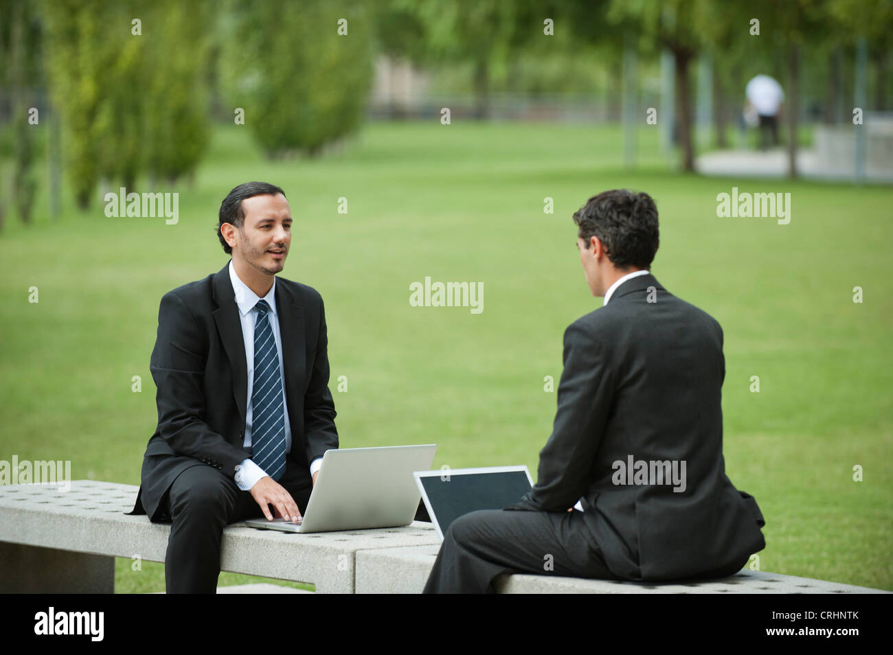 Business executives discussing work while using laptop computers ...