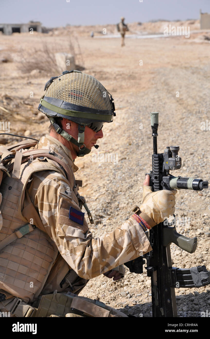 A soldier inspects his rifle at a checkpoint, afghanistan Stock Photo ...