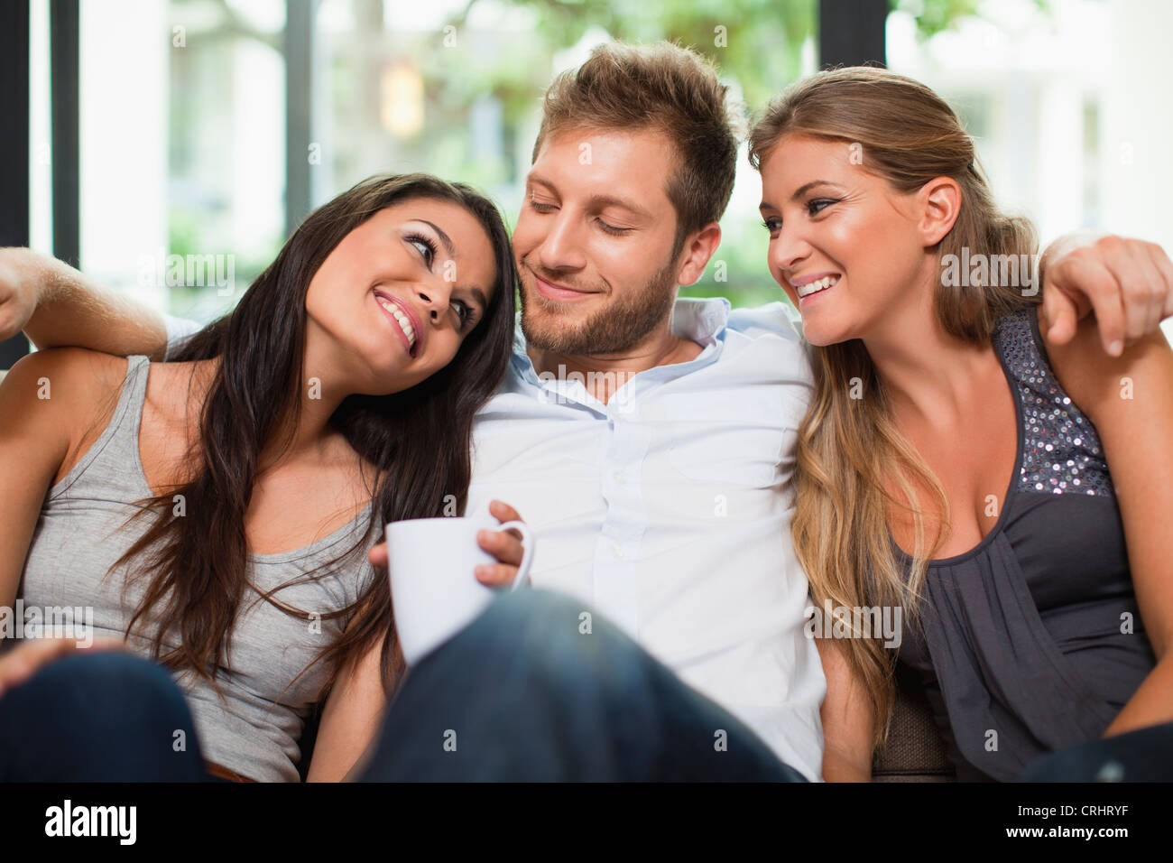 Friends having coffee together on sofa Stock Photo - Alamy