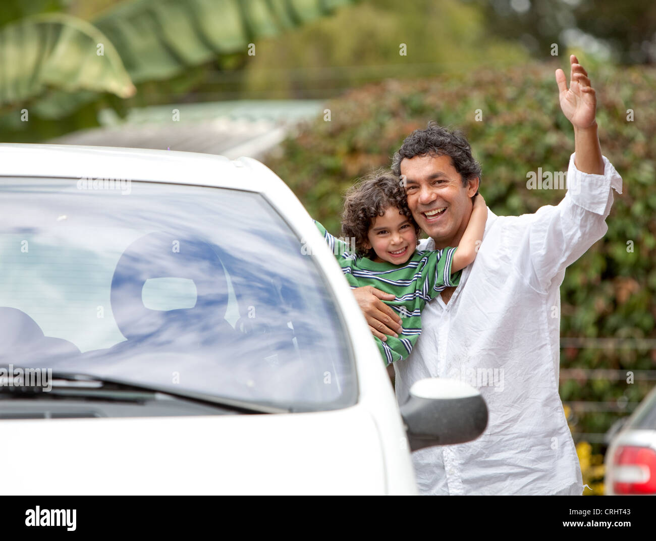 Father and son smiling with a car outdoors, ready to start in vacations ...