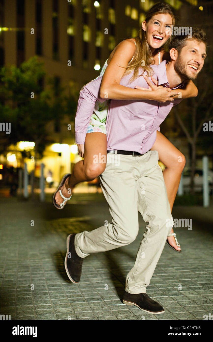 Man carrying girlfriend on city street Stock Photo - Alamy