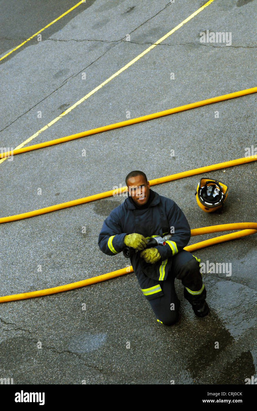 A fire fighter prepares to use a water hose to douse a fire Stock Photo ...