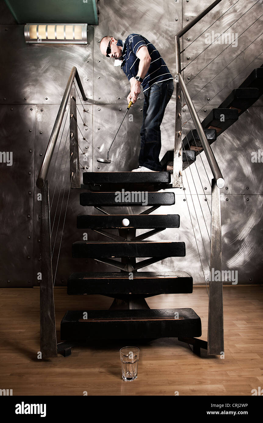 Man playing golf downstairs Stock Photo - Alamy