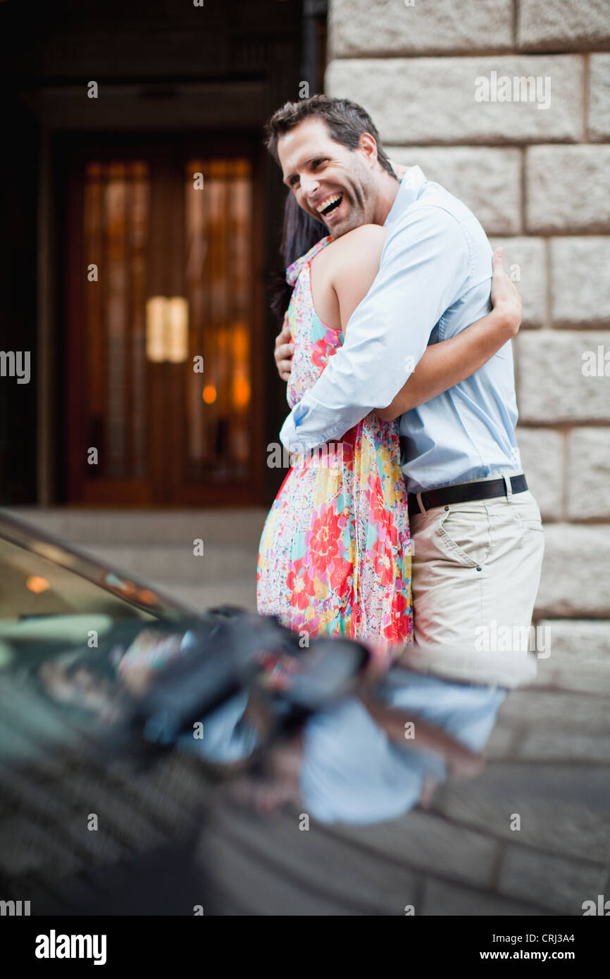 Couple hugging by car on city street Stock Photo - Alamy