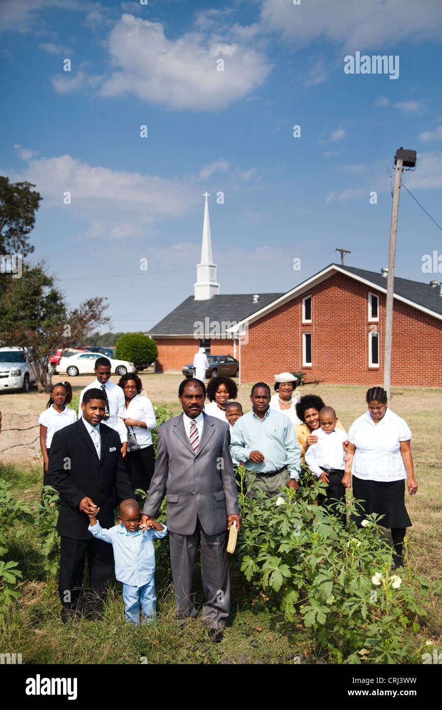 A small congregation stands in a garden in the backyard of a rural ...