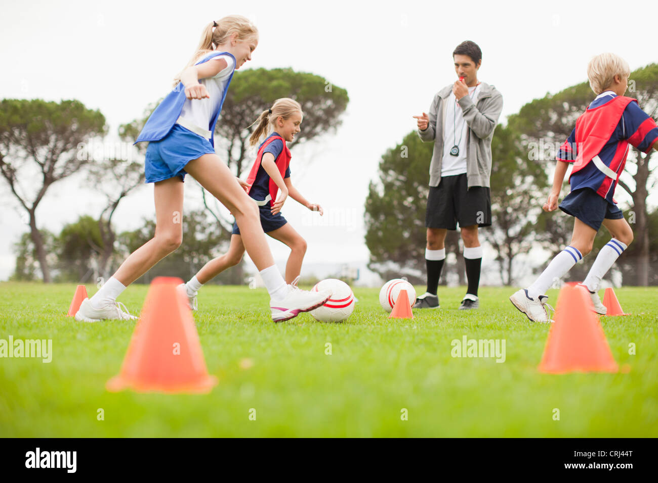 Coach training childrens soccer team Stock Photo - Alamy