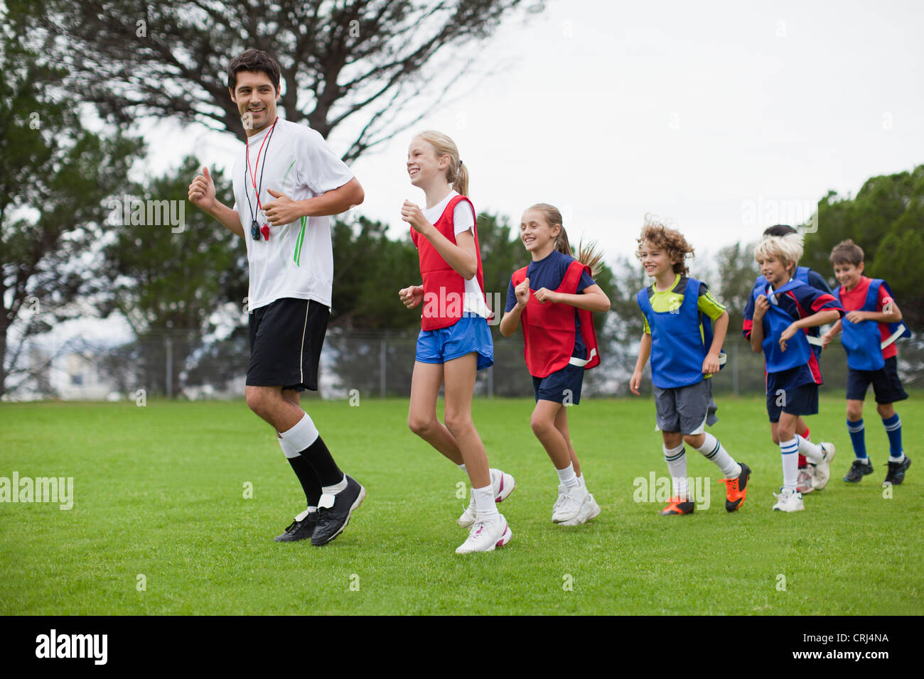 Coach training children on field Stock Photo - Alamy