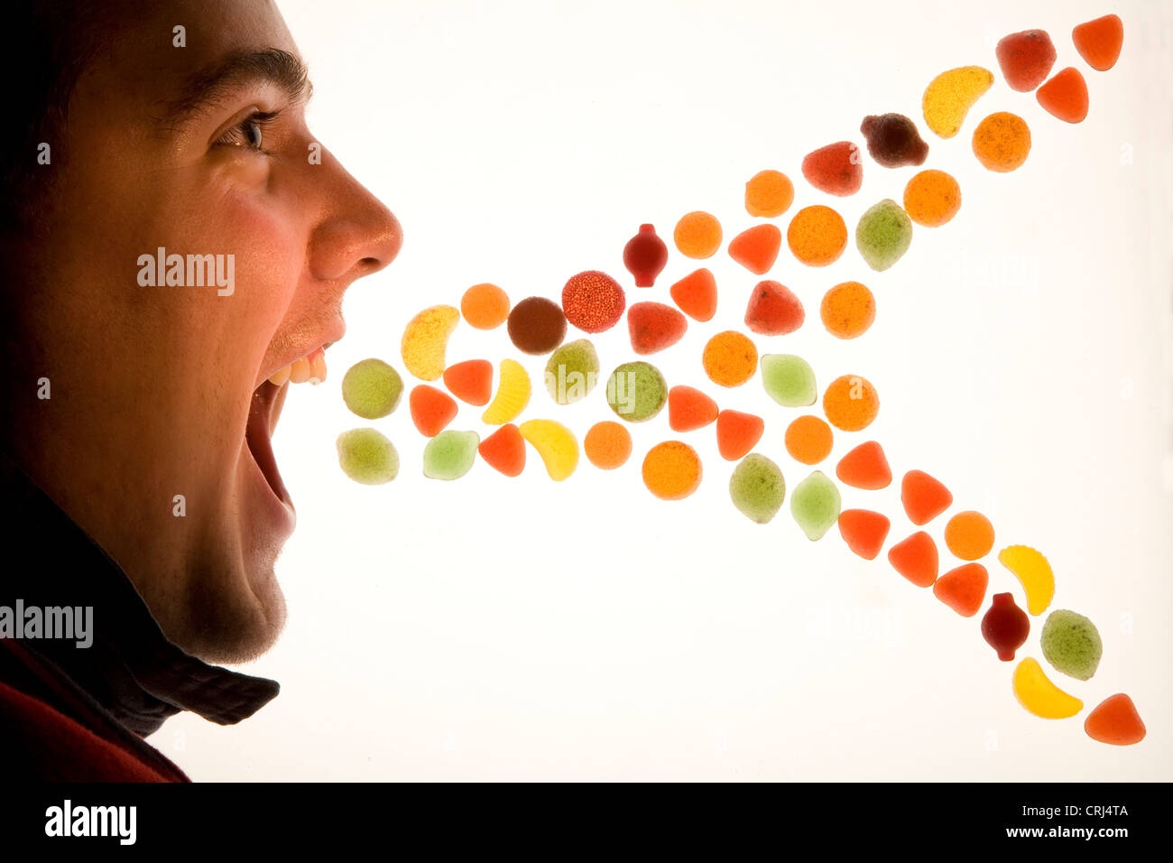 Profile of a young man eating a large assortment of sweets Stock Photo ...