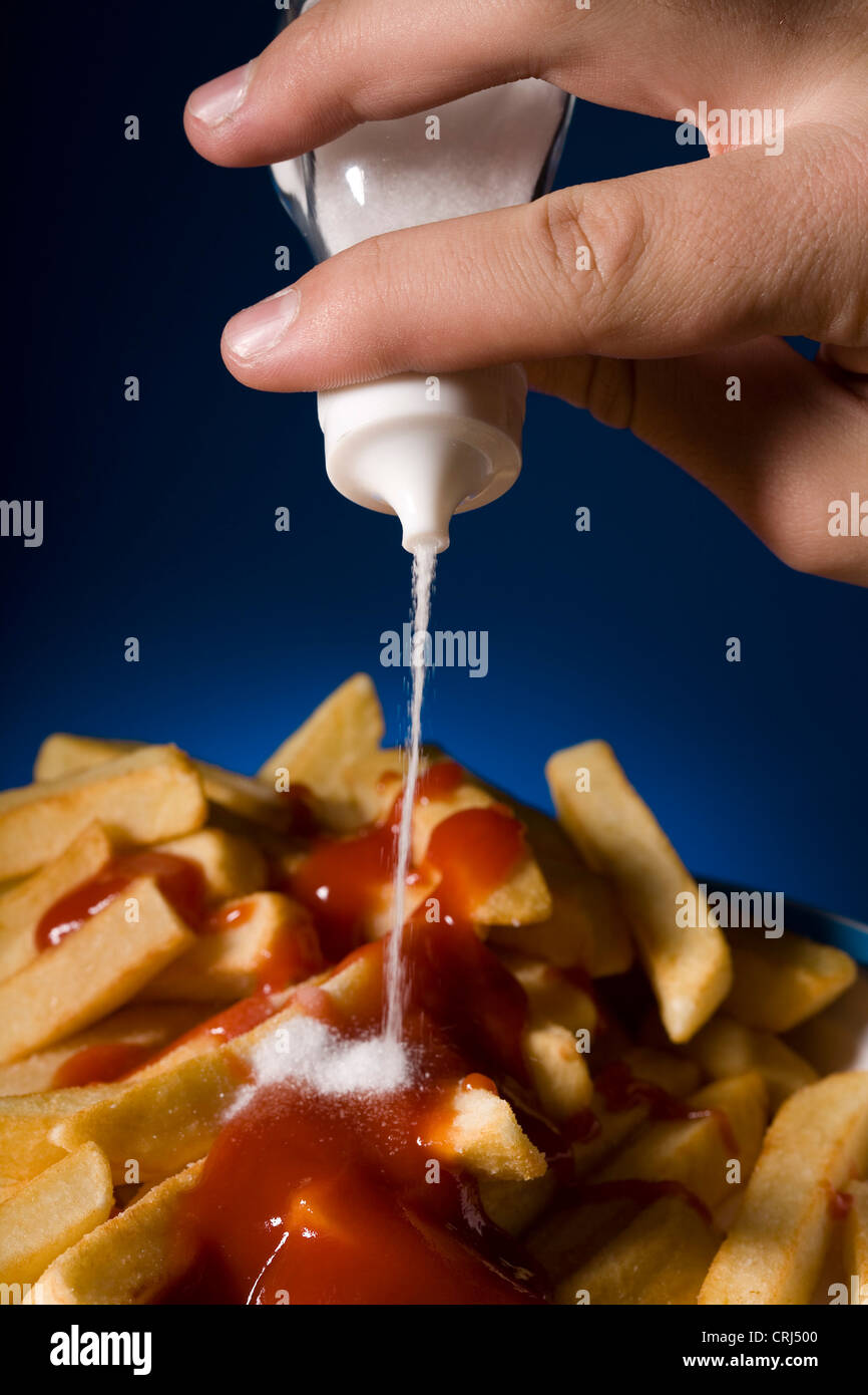 Salt being poured onto a large pile of chips Stock Photo - Alamy