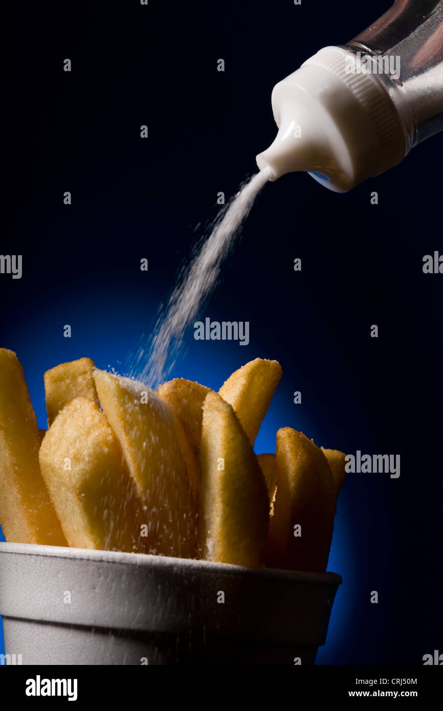 Salt being poured onto a cupful of chips Stock Photo - Alamy