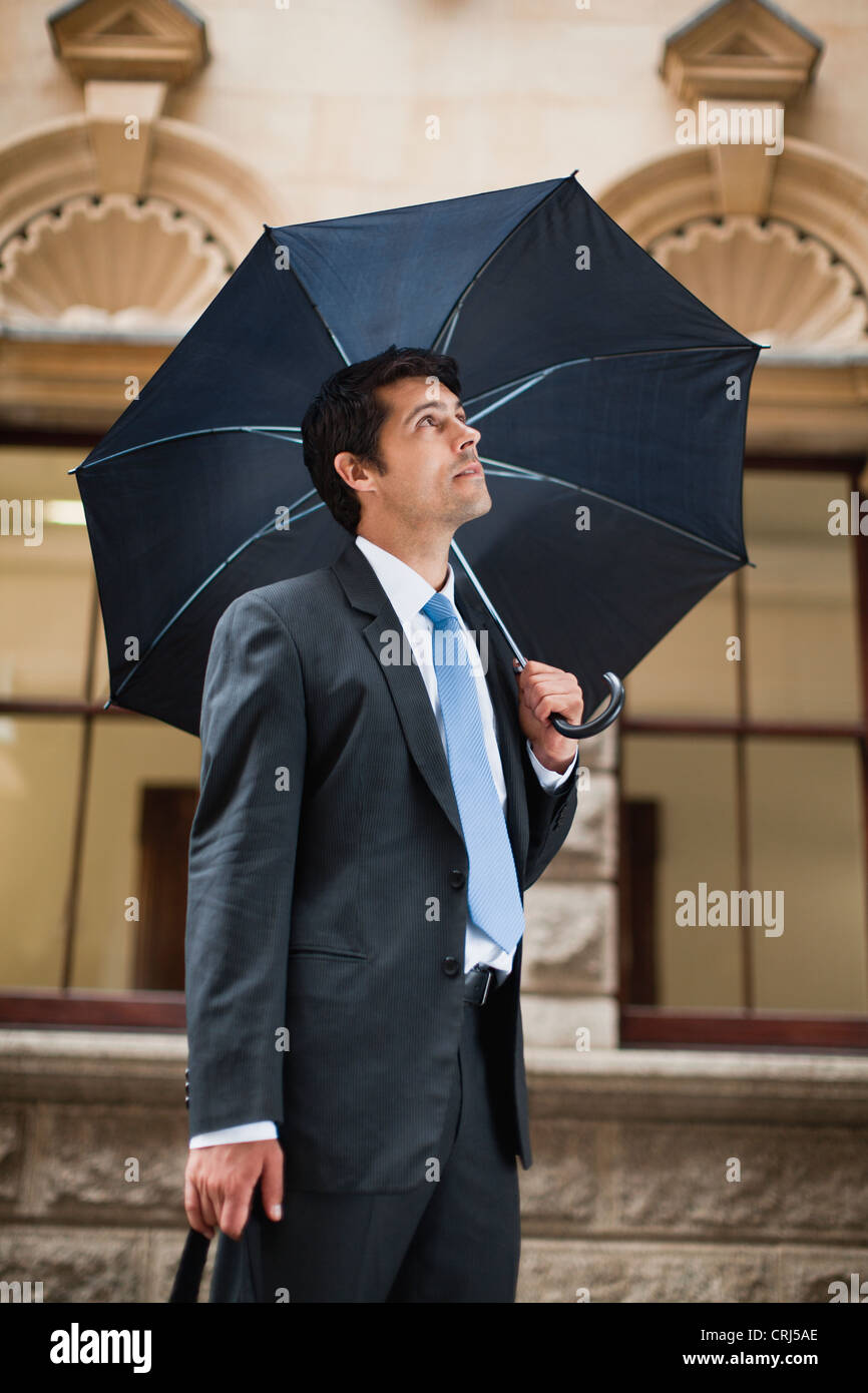 Businessman carrying umbrella on street Stock Photo - Alamy