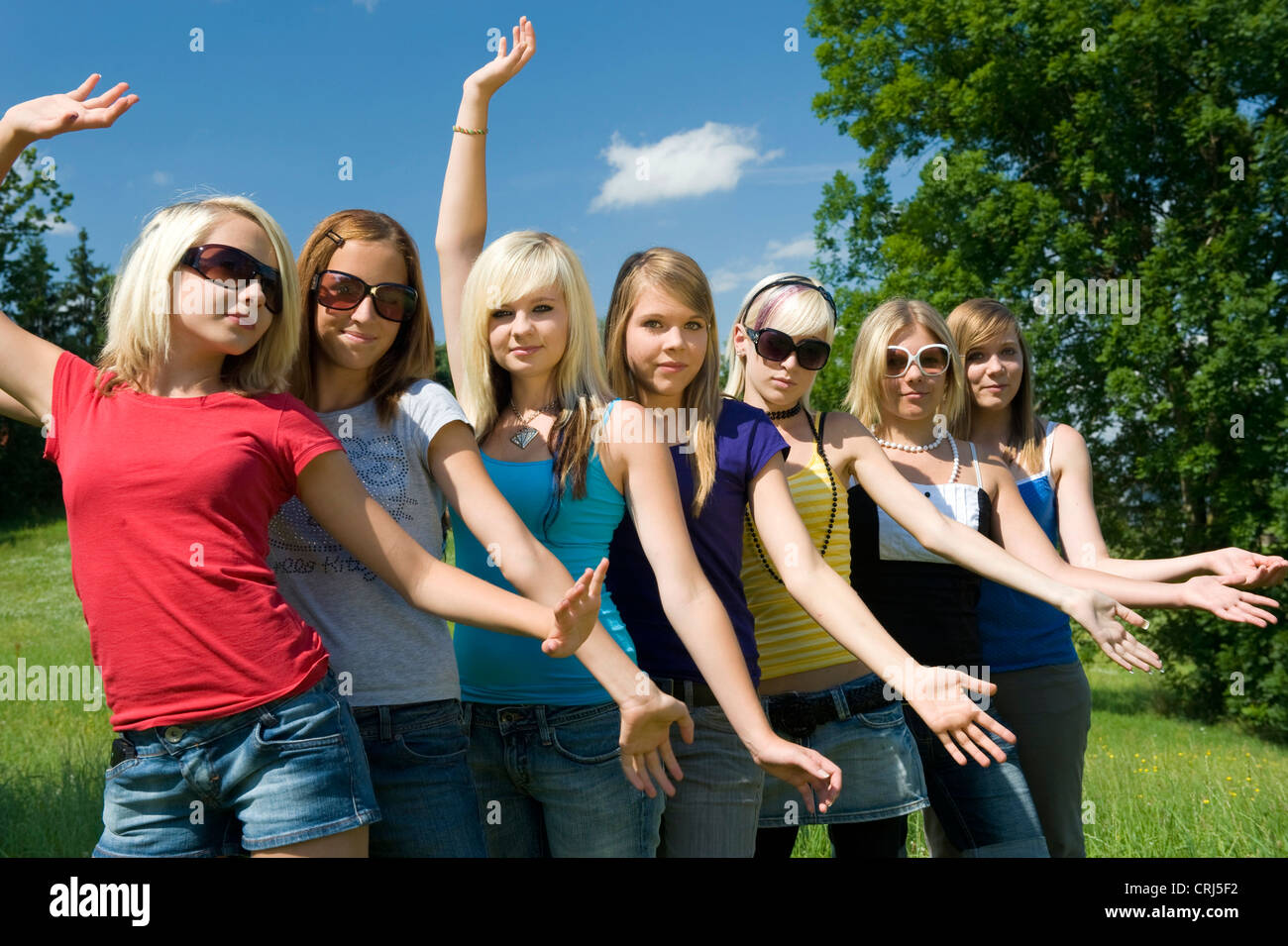 group of teenage girls posing in a meadow in a row behind each other ...