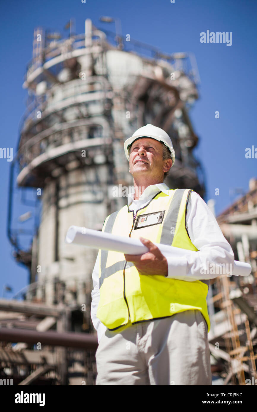Worker with blueprints at oil refinery Stock Photo - Alamy