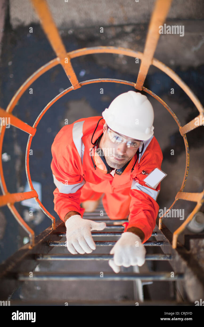 Worker climbing ladder at oil refinery Stock Photo - Alamy