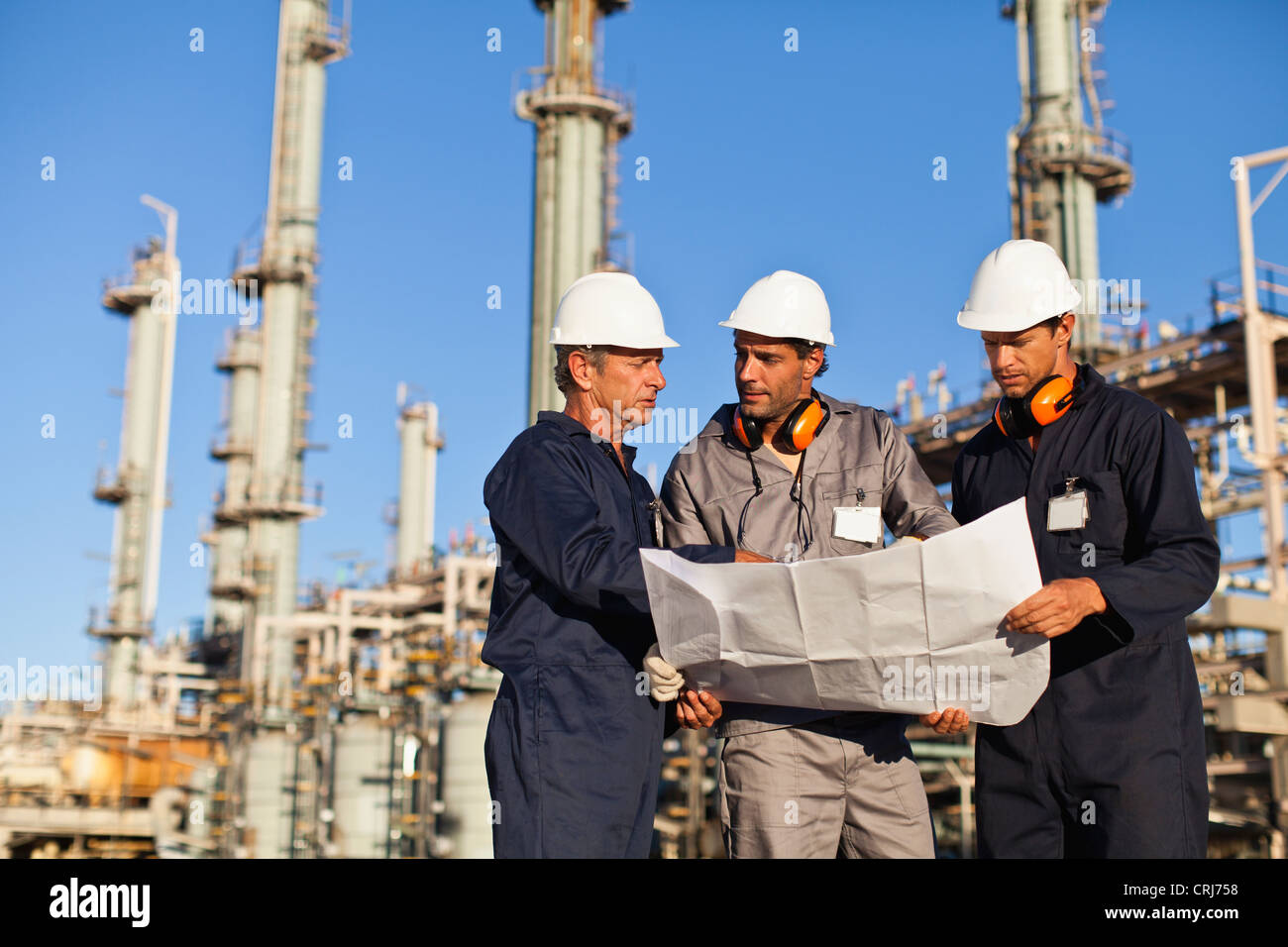 Workers with blueprints at oil refinery Stock Photo - Alamy