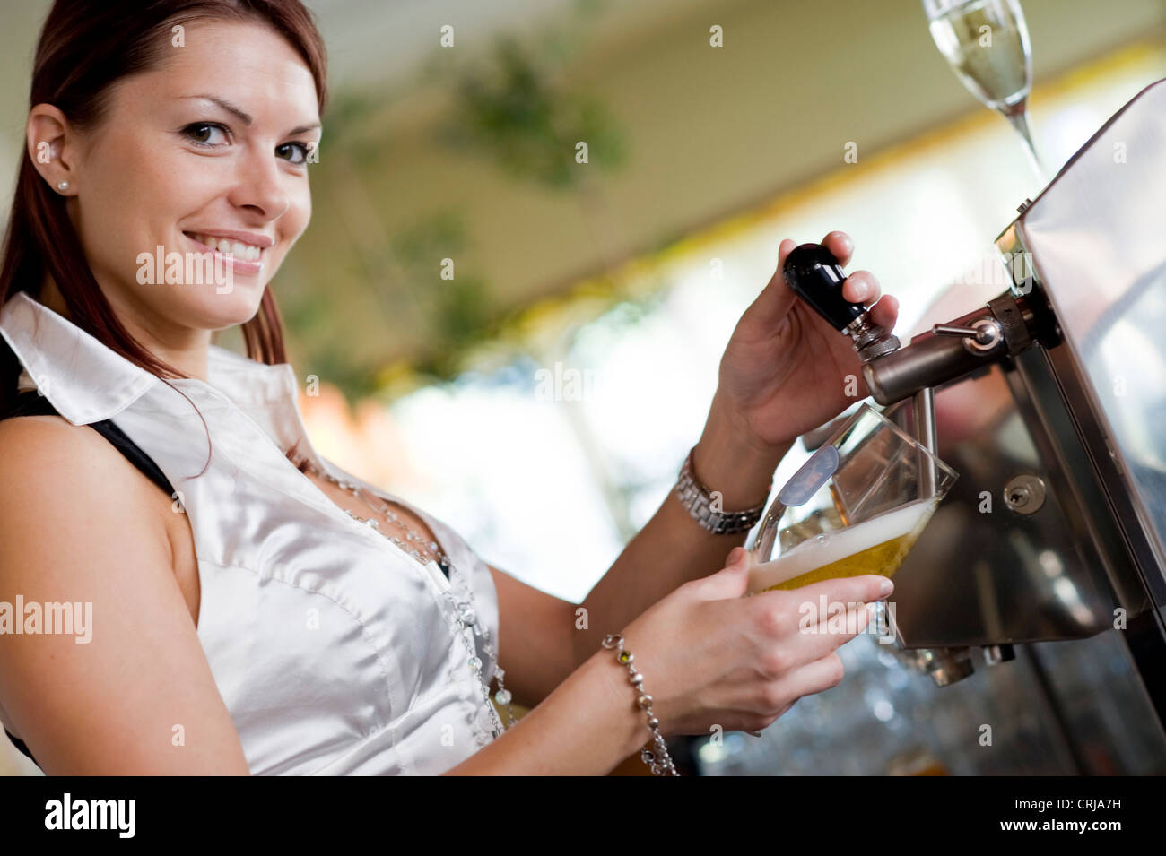 young waitress behind the bar drawing beer with a smile Stock Photo - Alamy