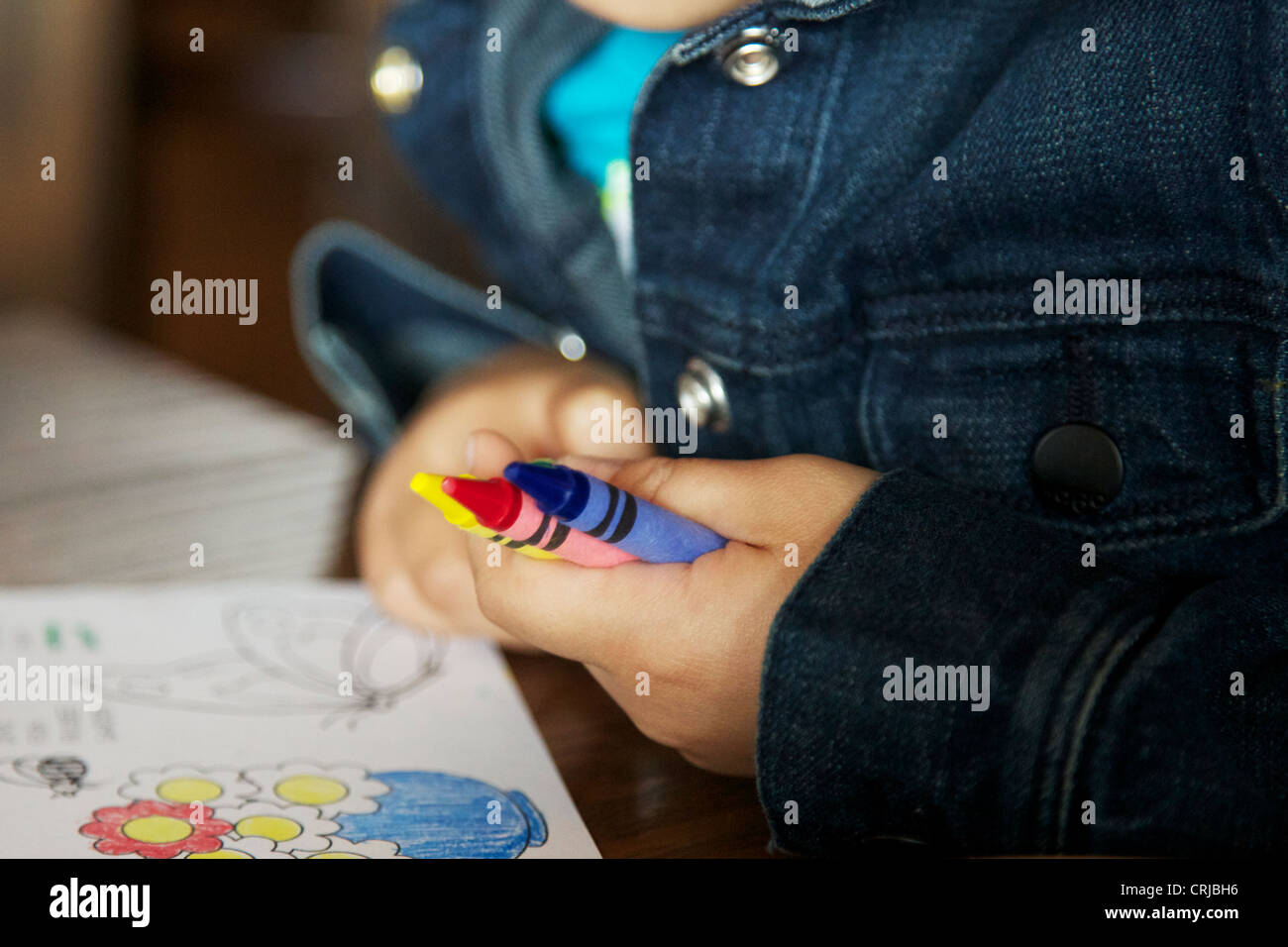 Girl's hand holding red, yellow and blue crayons Stock Photo - Alamy