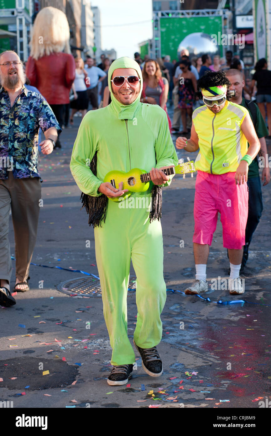 Zany character with miniature guitar walking on Ste-Catherine street ...