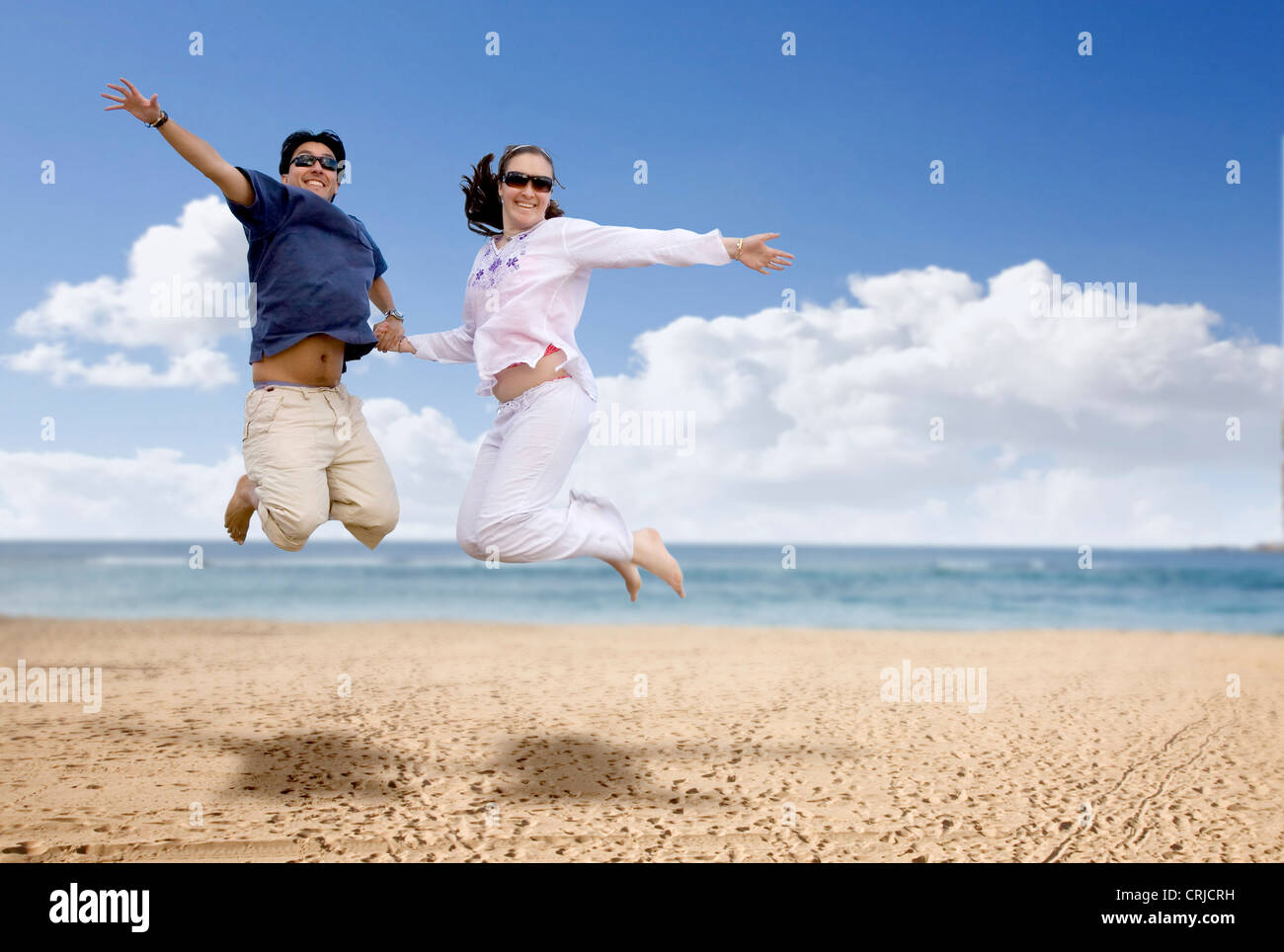 couple in love jumping of joy at the beach on a sunny day Stock Photo ...