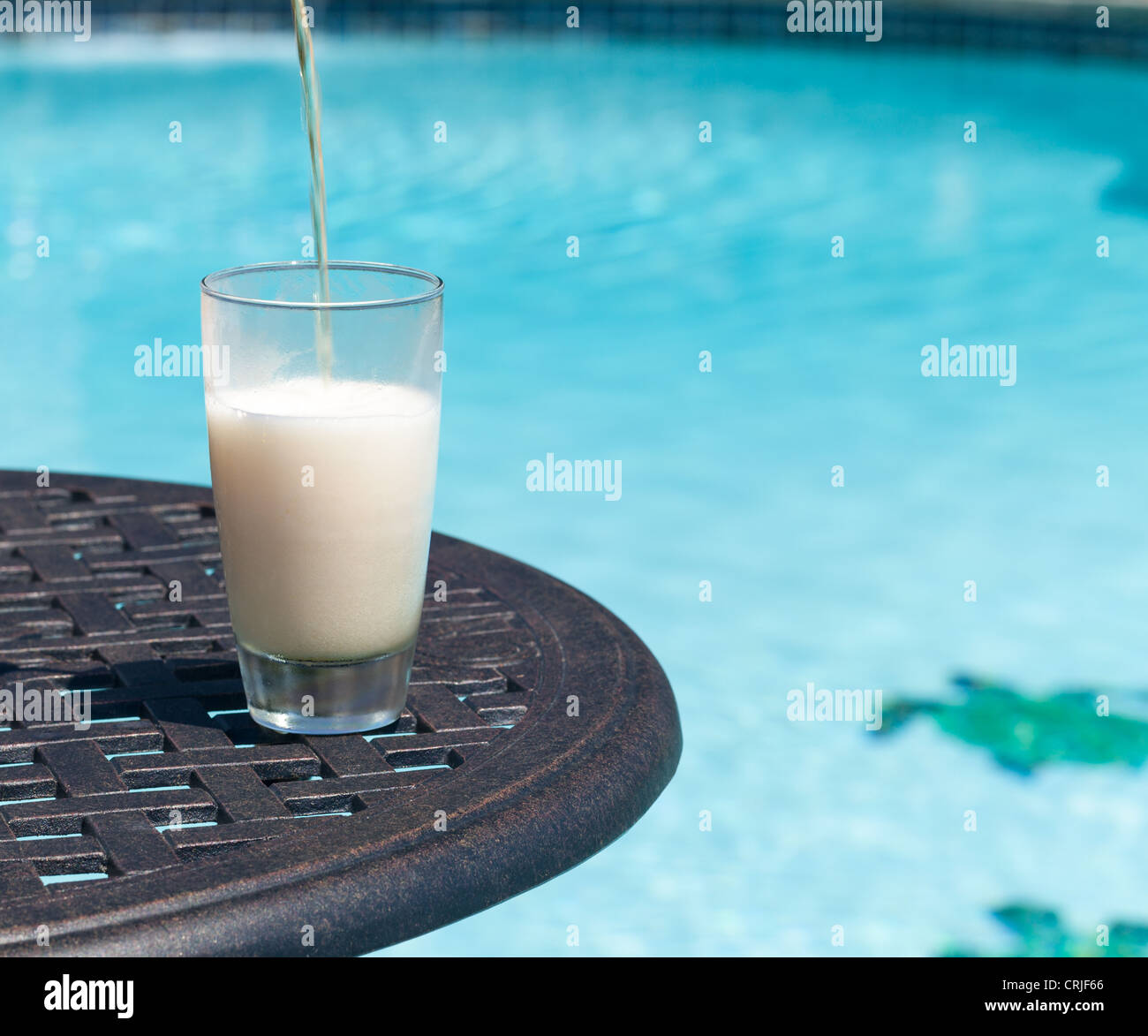 Plain pint glass of beer being poured sitting on table by blue swimming ...