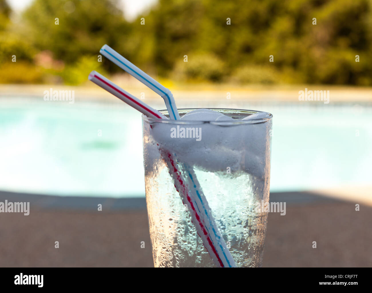 Plain glass of water with ice cubes on side of blue swimming pool Stock ...