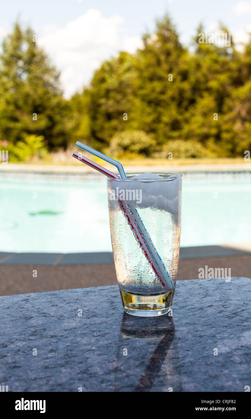 Plain glass of water with ice cubes on side of blue swimming pool Stock ...
