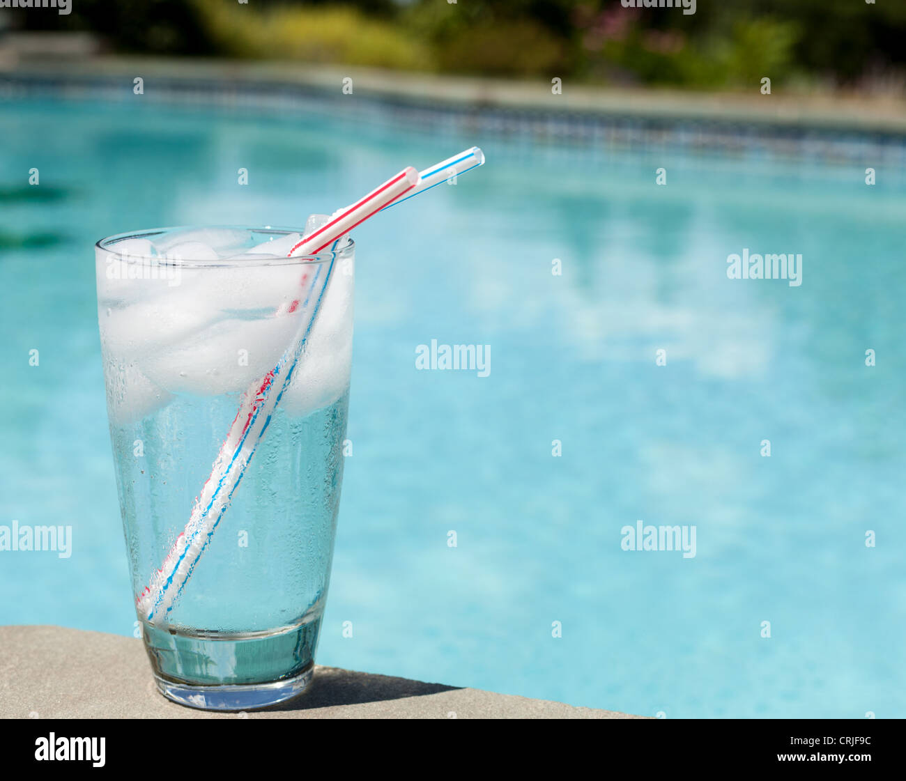 Plain glass of water with ice cubes on side of blue swimming pool Stock ...