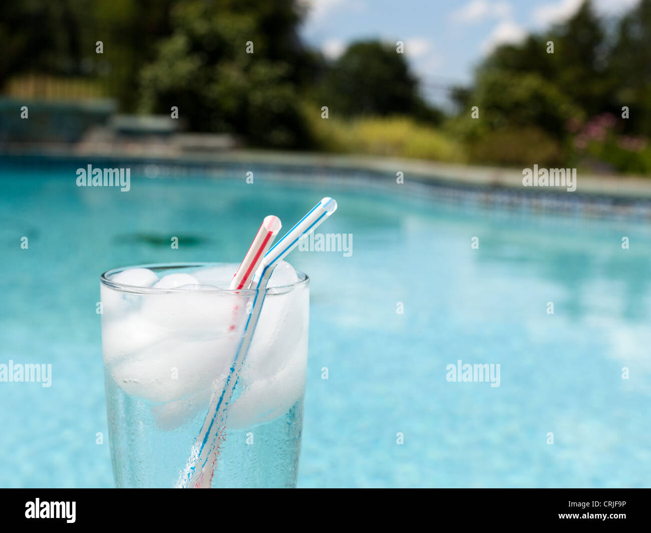 Plain glass of water with ice cubes on side of blue swimming pool Stock ...