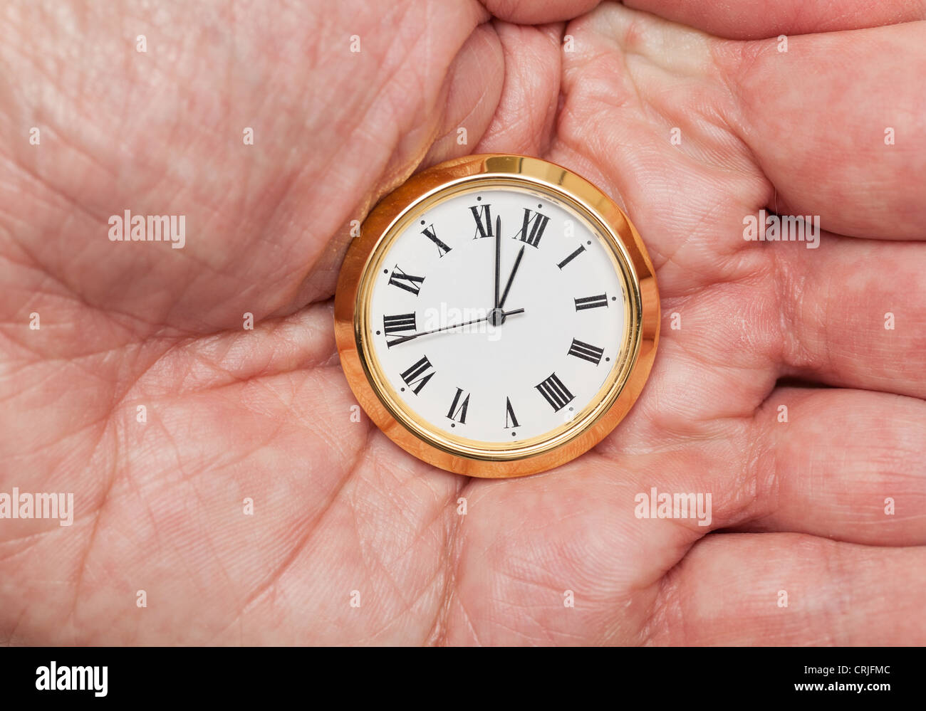 Small gold colored clock almost at midnight held in palm of hand Stock ...