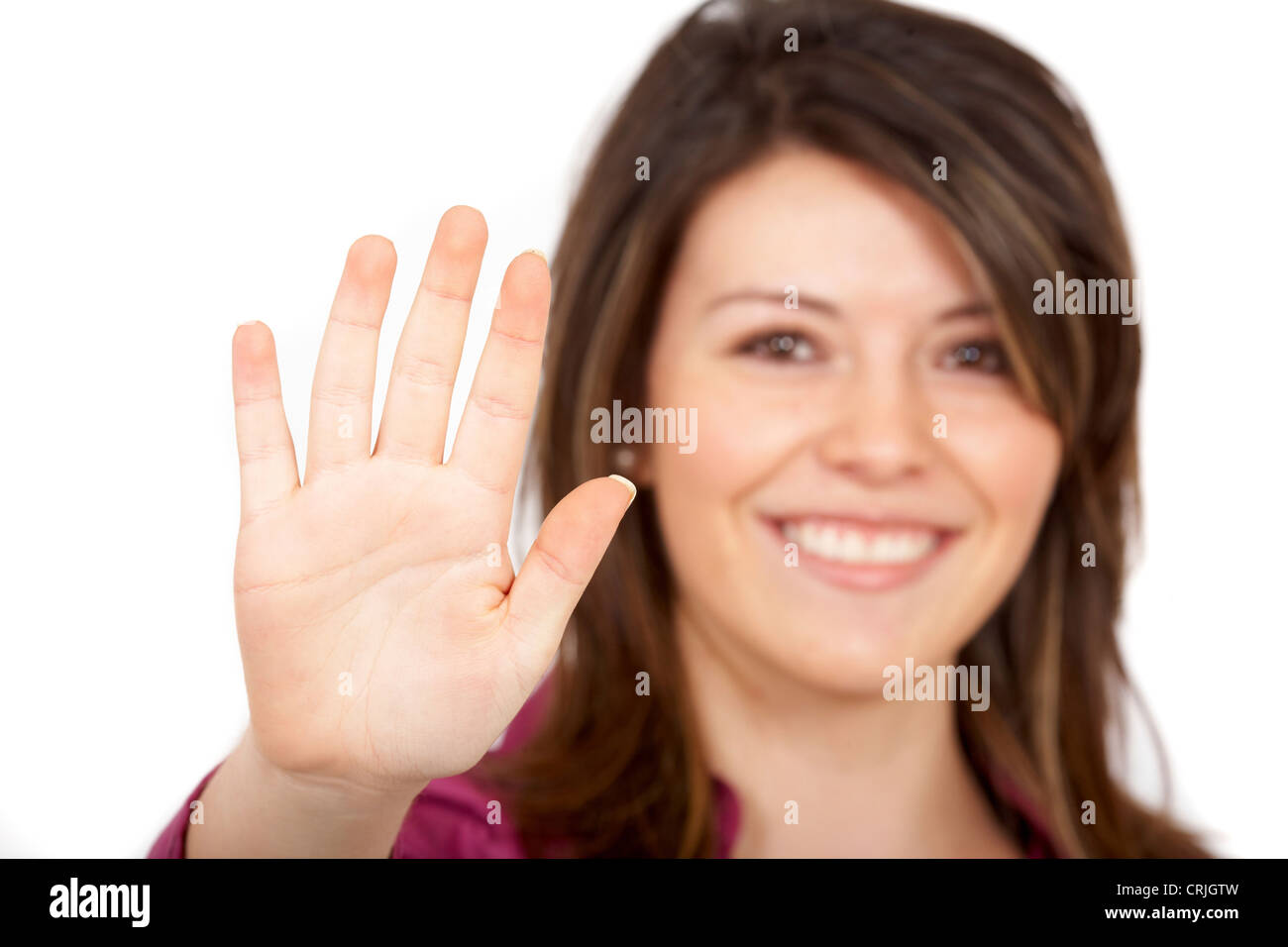 brunette young woman lifting one hand with a smile Stock Photo - Alamy