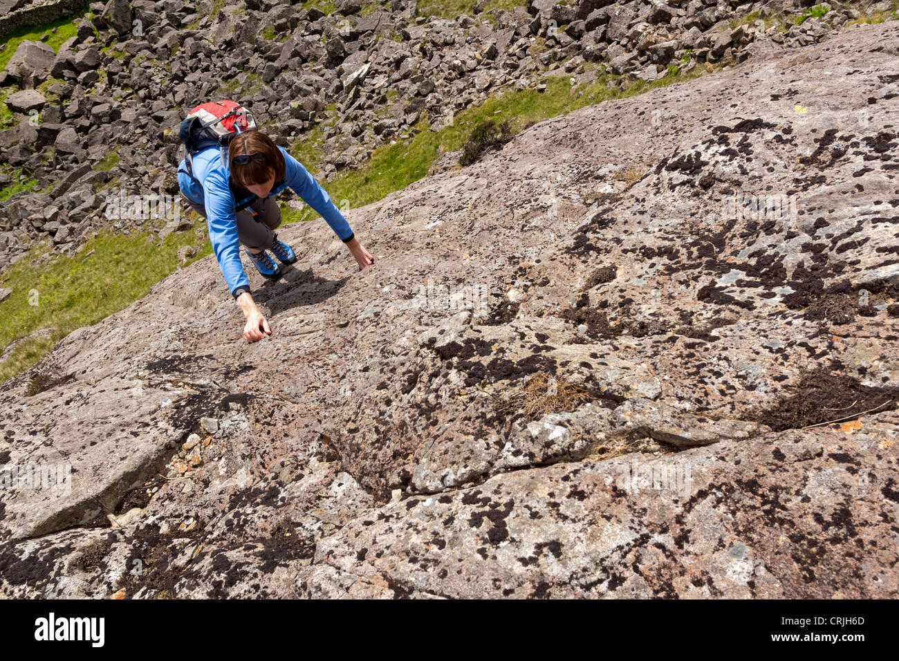 A female rock scrambler ascends a steep section of rock on a scramble ...