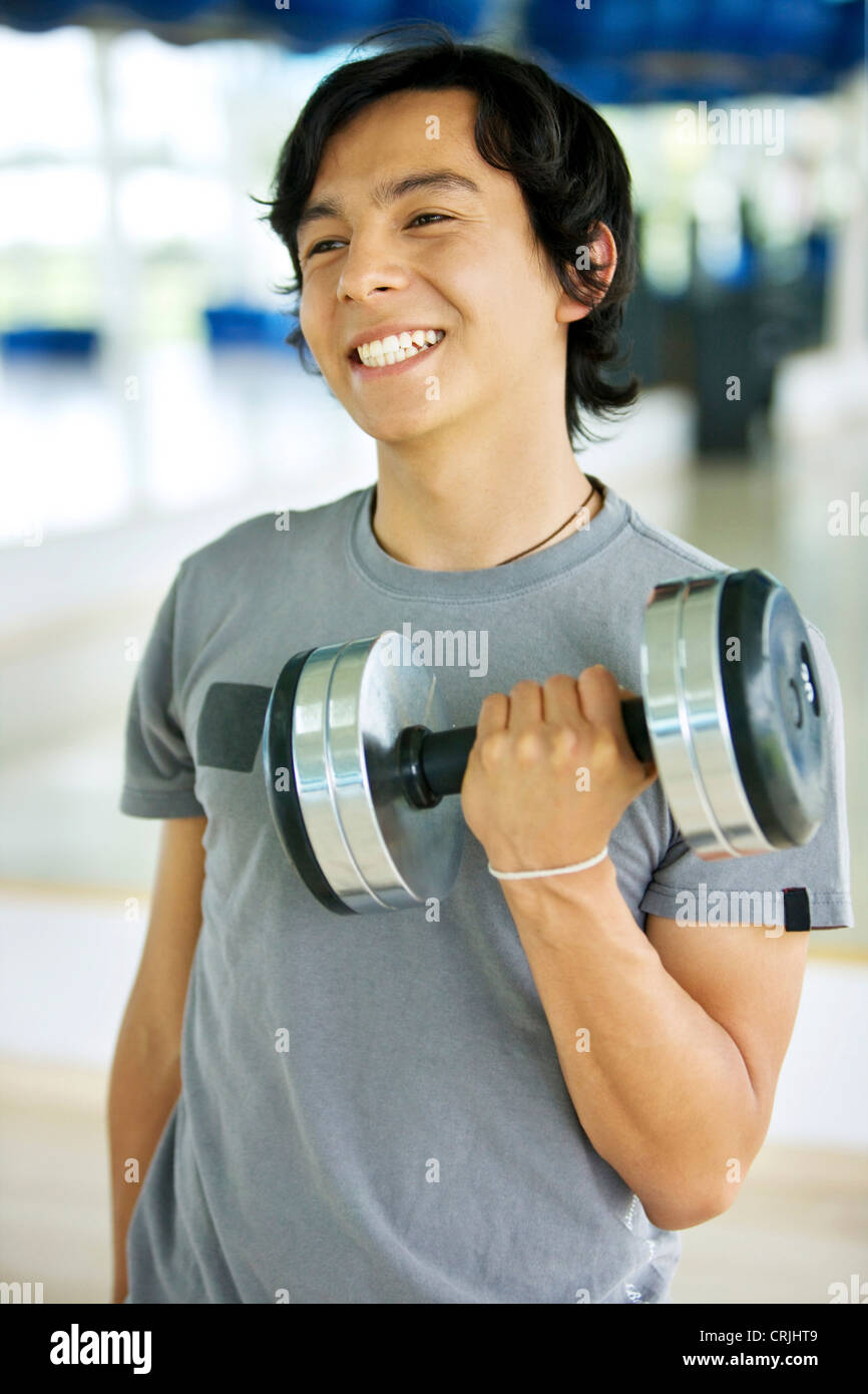 Man at the gym exercising with free weights Stock Photo - Alamy