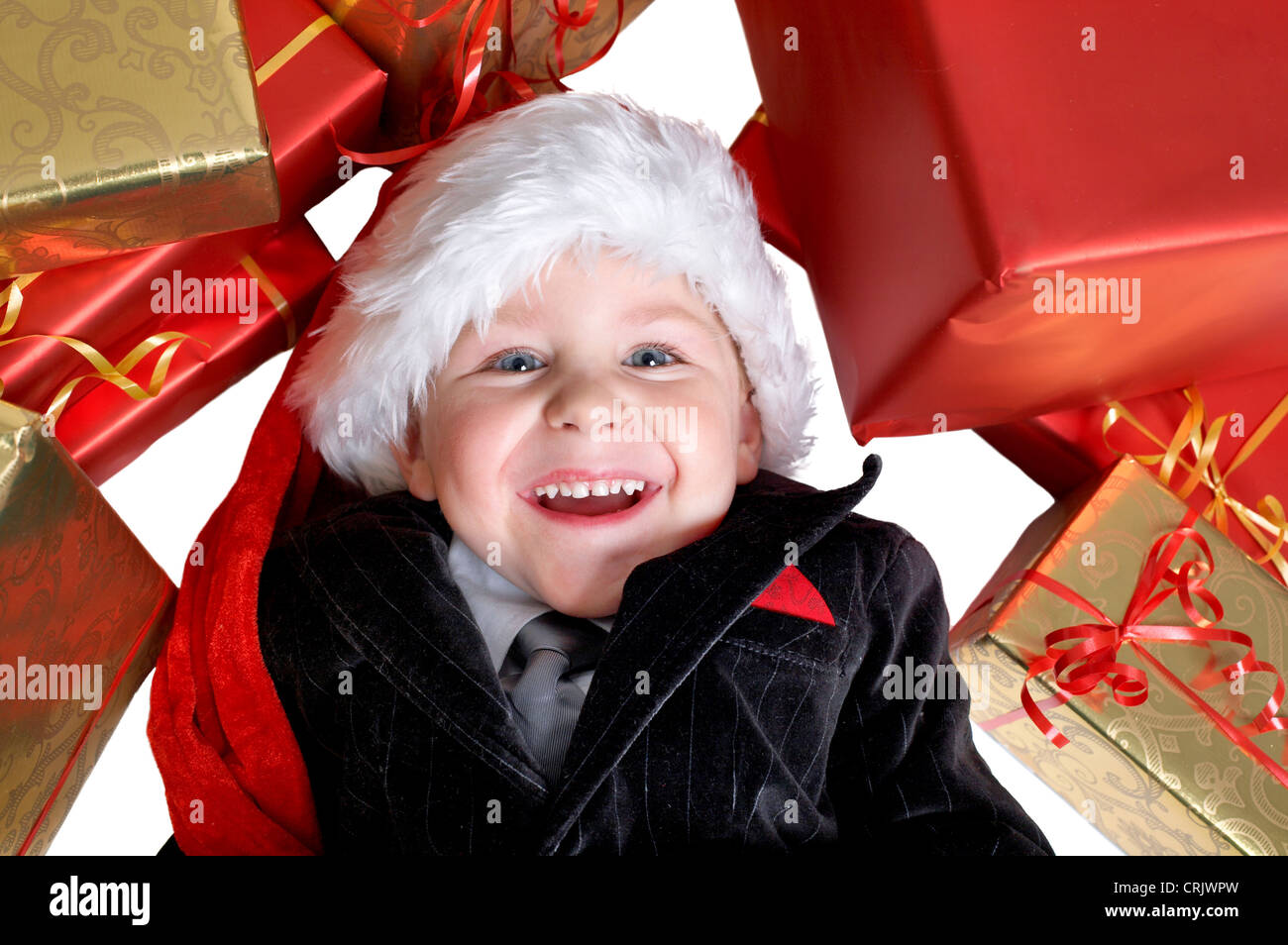 young boy with a Santa cap surrounded by Christmas presents with a ...