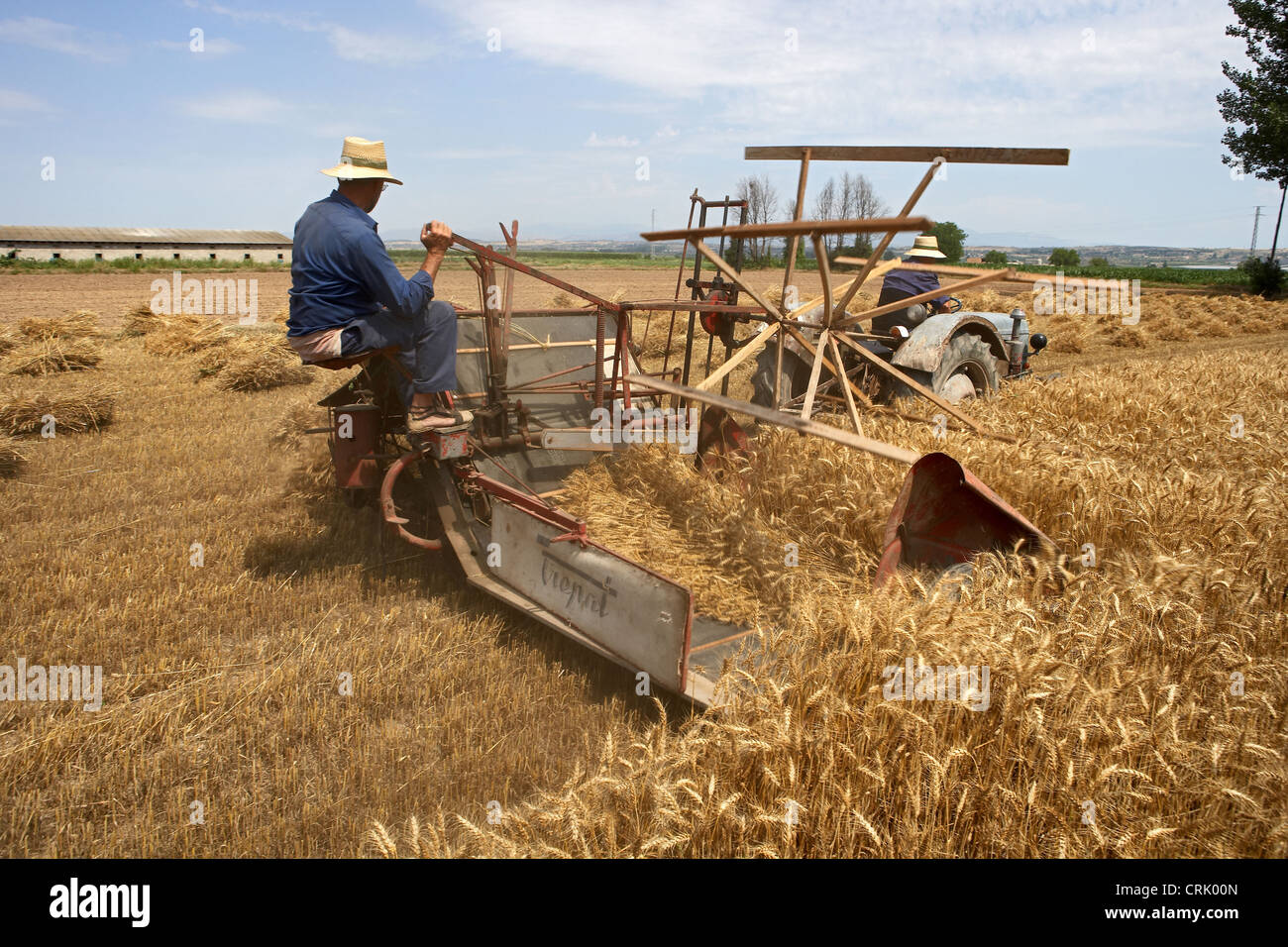 Old agricultural machine harvesting with tractor Stock Photo - Alamy