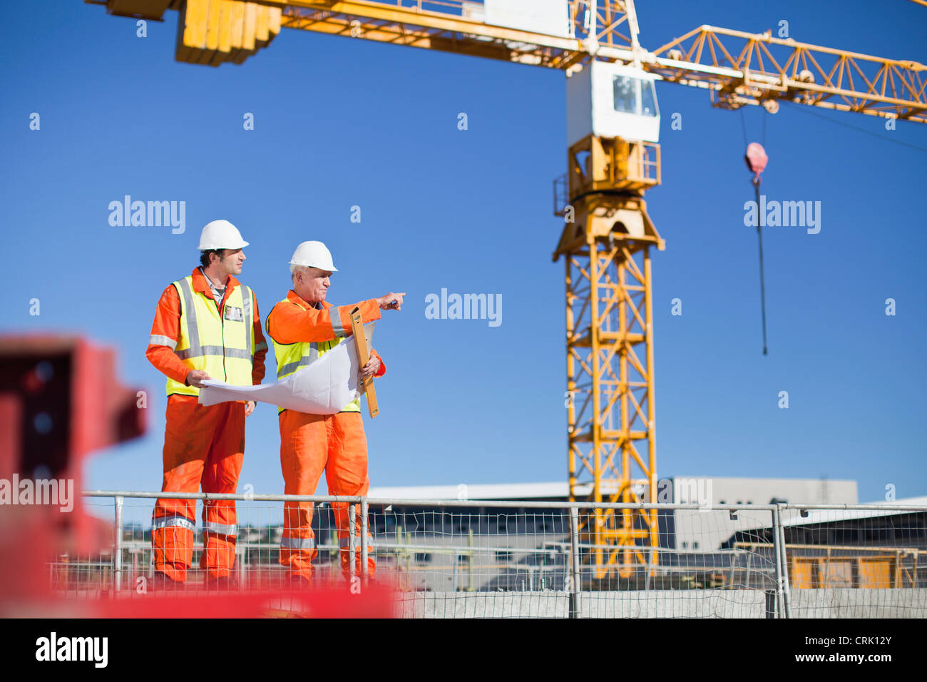 Workers reading blueprints on site Stock Photo - Alamy