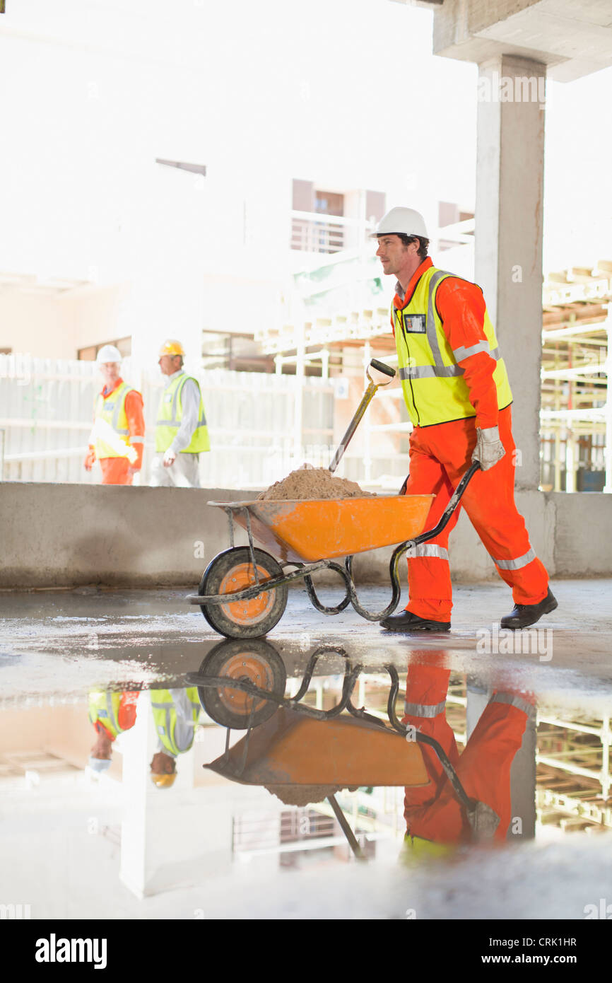 Worker carting concrete on site Stock Photo - Alamy