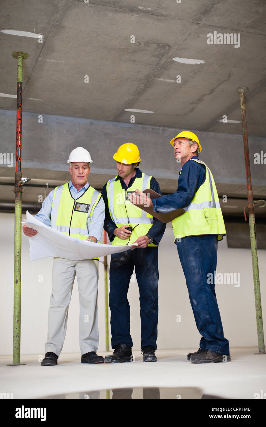 Workers reading blueprints on site Stock Photo - Alamy