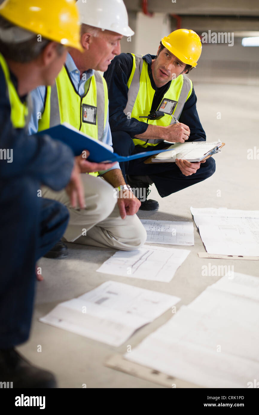 Workers reading blueprints on site Stock Photo - Alamy