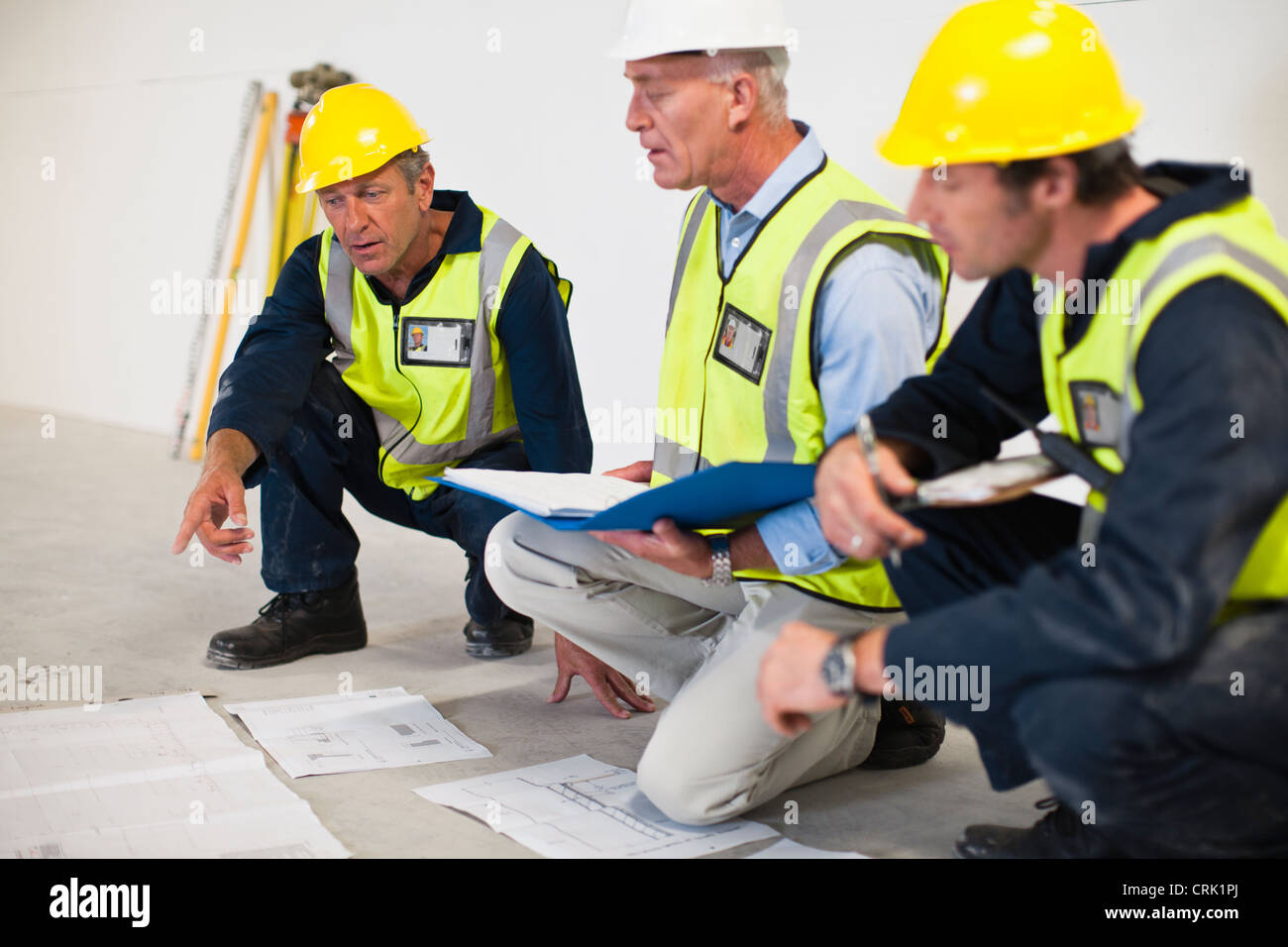 Workers reading blueprints on site Stock Photo - Alamy