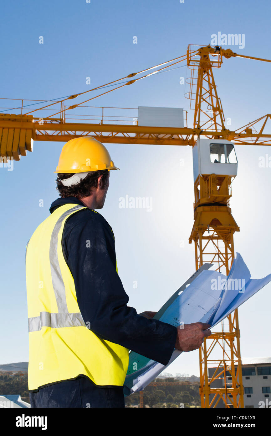 Worker reading blueprints on site Stock Photo - Alamy