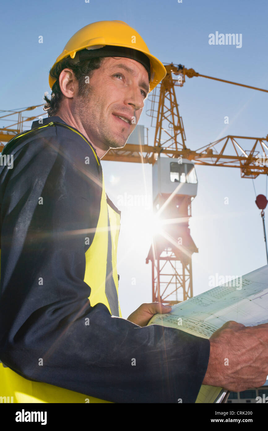 Worker reading blueprints on site Stock Photo - Alamy