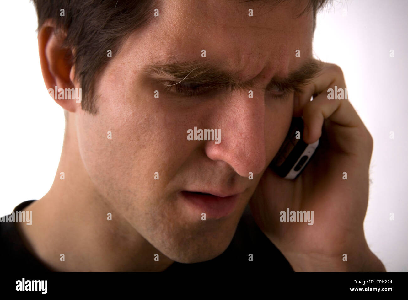 A worried young man talking on a mobile phone Stock Photo - Alamy