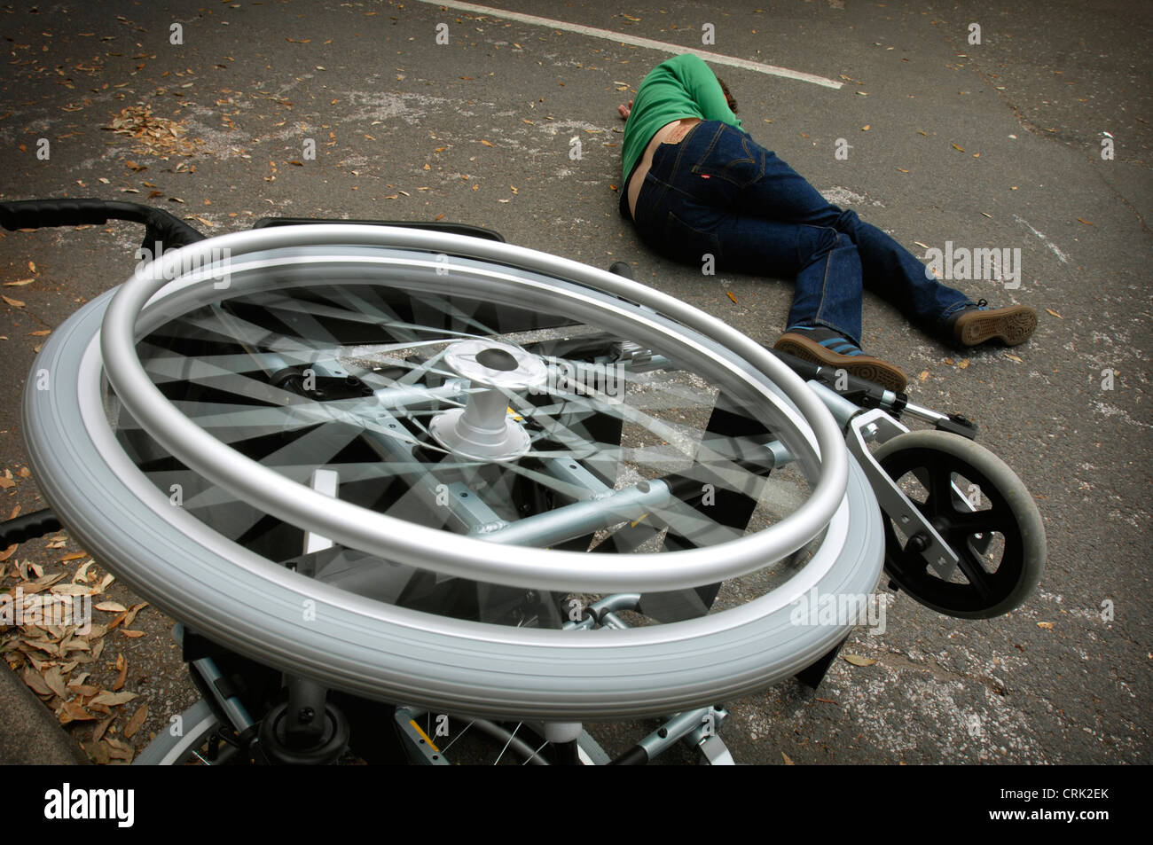 A young man lies on the ground, after falling out of his wheelchair ...
