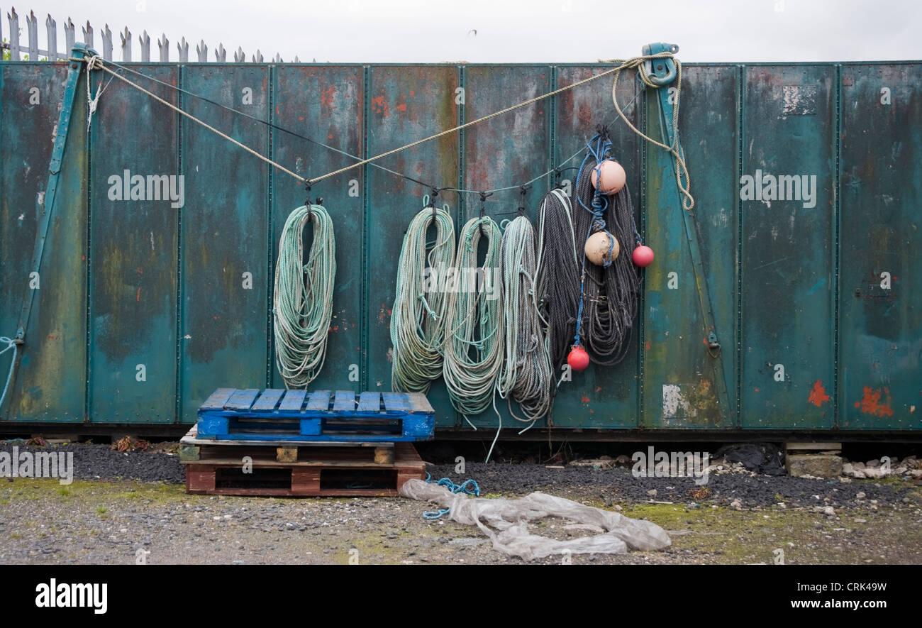Coils of rope & net floats hanging from a green sea container ...