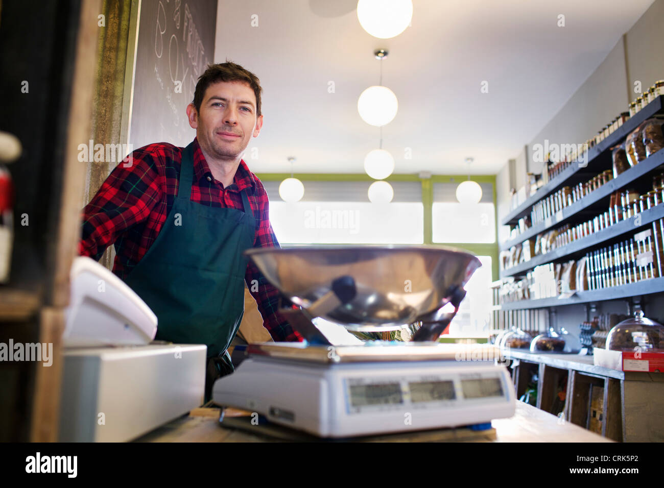 Grocer working behind counter at store Stock Photo - Alamy