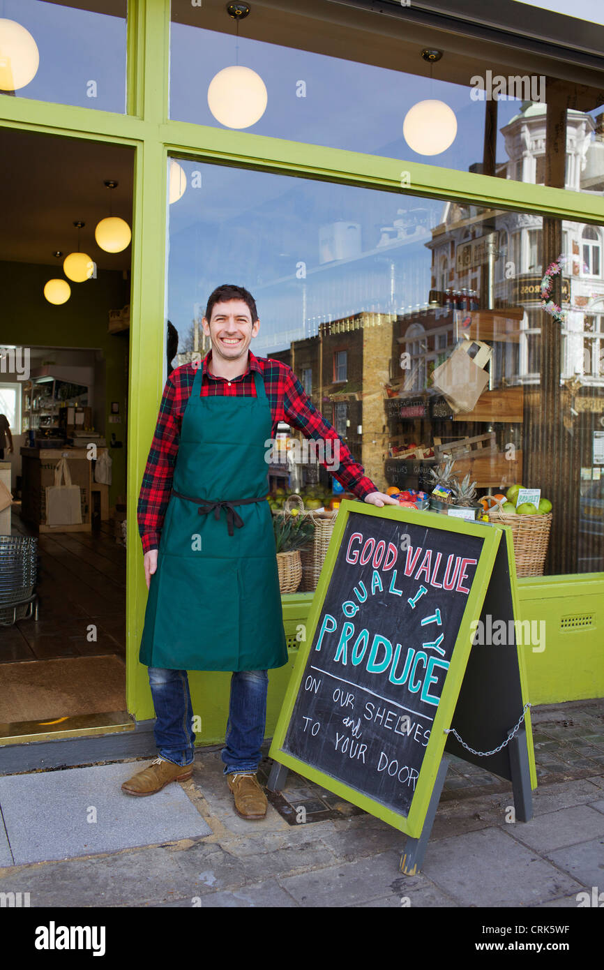 Smiling grocer standing outside store Stock Photo - Alamy