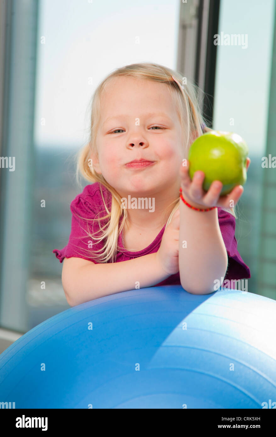 Girl eating apple on exercise ball Stock Photo - Alamy