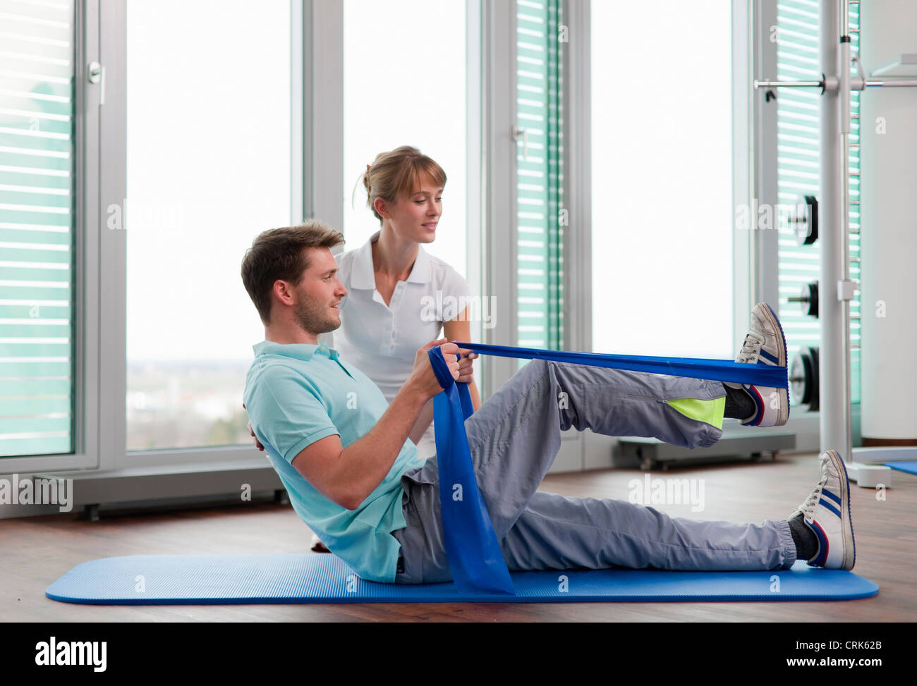 Trainer working with man in gym Stock Photo - Alamy