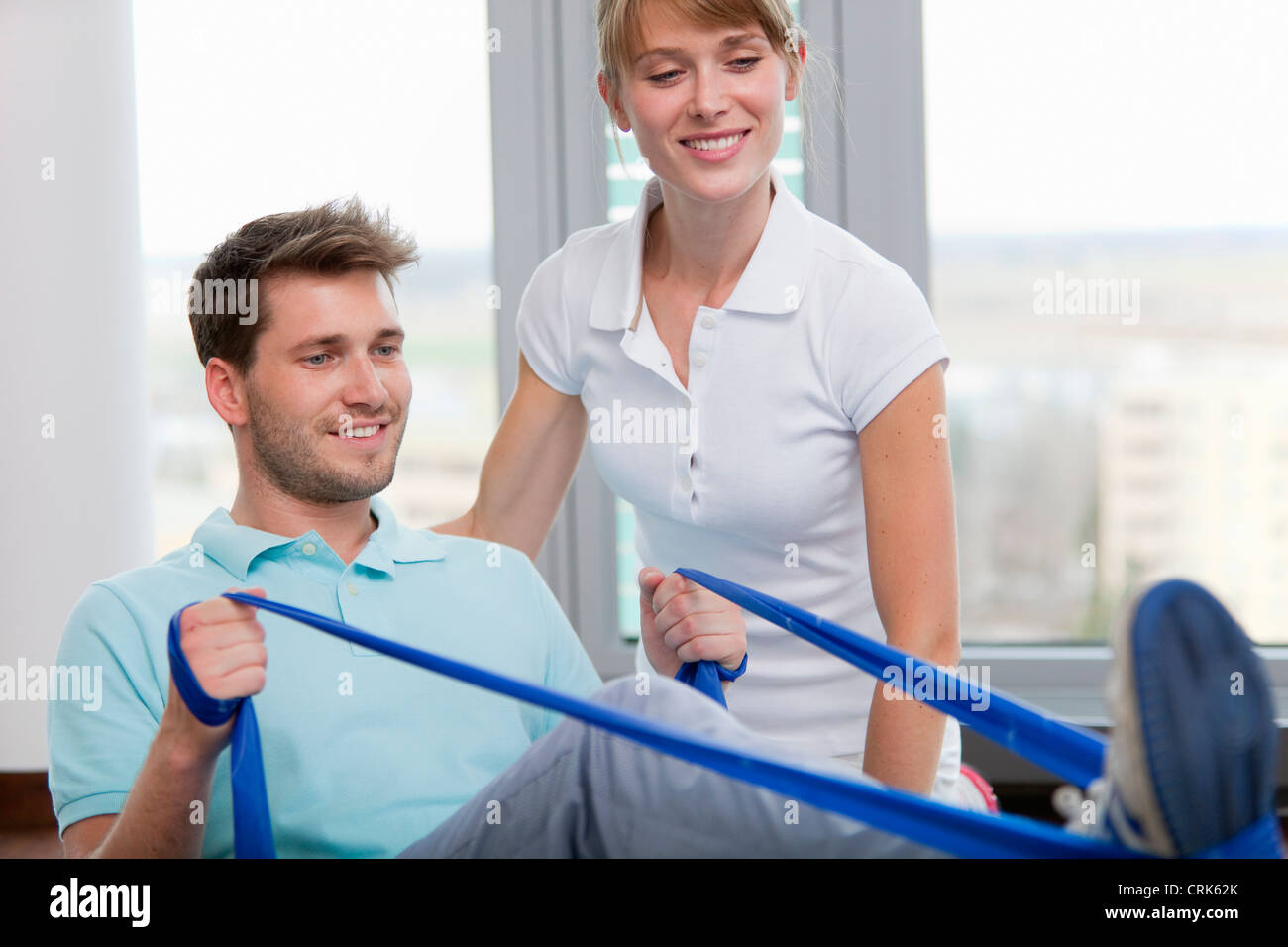 Trainer working with man in gym Stock Photo - Alamy
